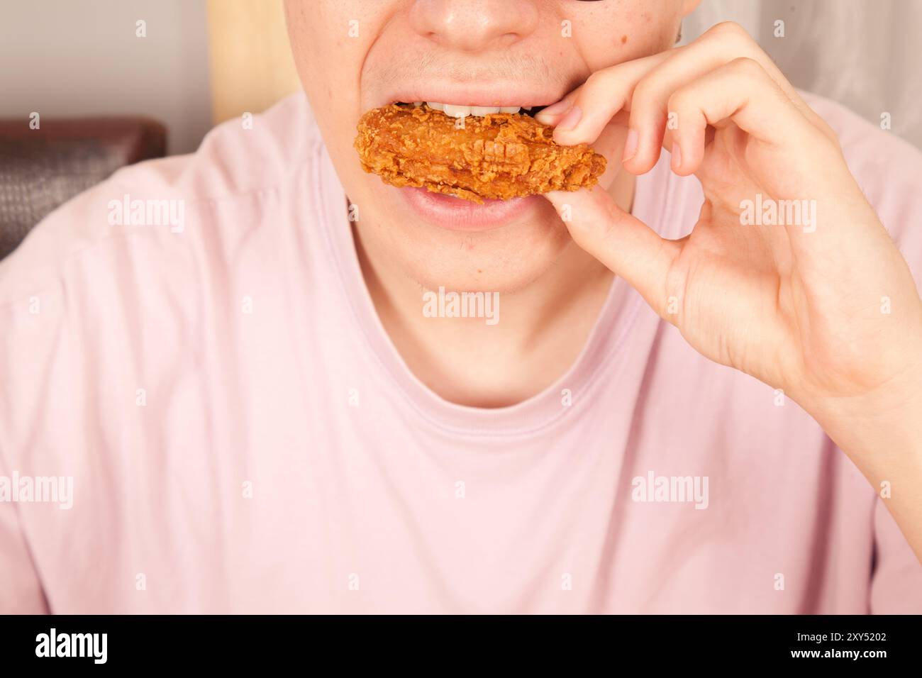 Caucasian man eating golden fried chicken wings, American fast food ...