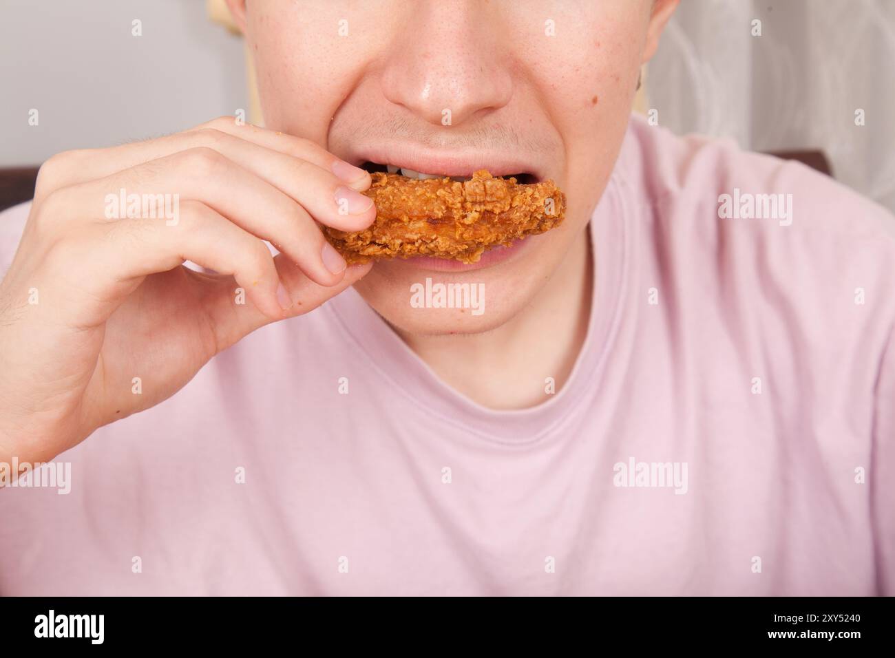 Caucasian man eating golden fried chicken wings, American fast food ...