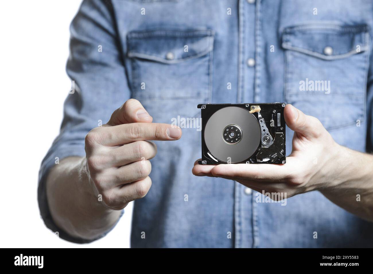 Man's hand holds a 2.5 inch hard drive. He's points to the hard disk ...