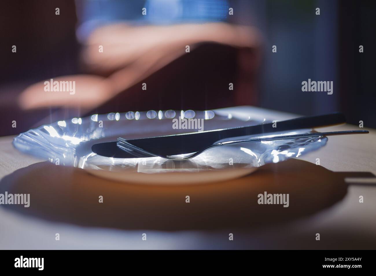 An empty breakfast plate with knife and fork stands on the table in the ...
