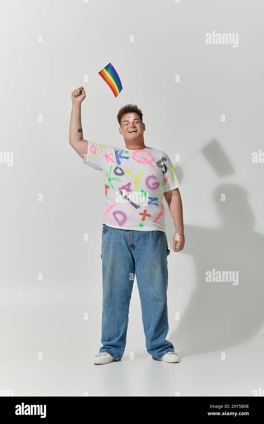 A young man smiles joyfully, holding a rainbow flag aloft Stock Photo ...