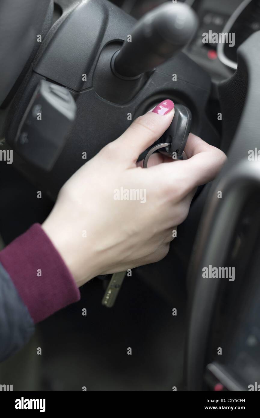 Closeup inside vehicle of hand holding key in ignition, steering wheel ...