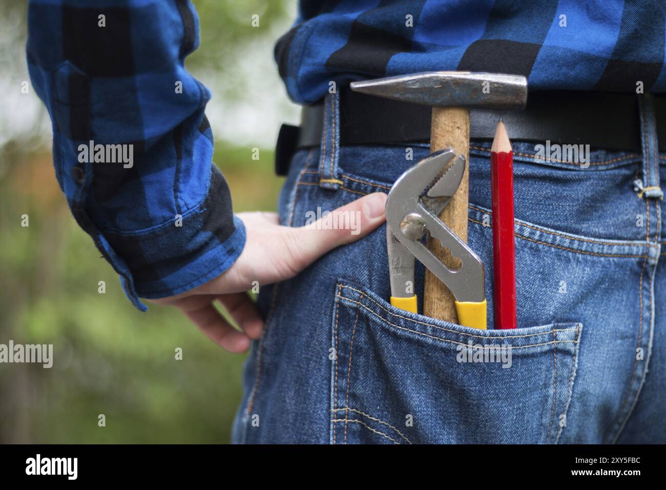 Close up picture of a craftsman with hammer, pencil and gripper in his ...