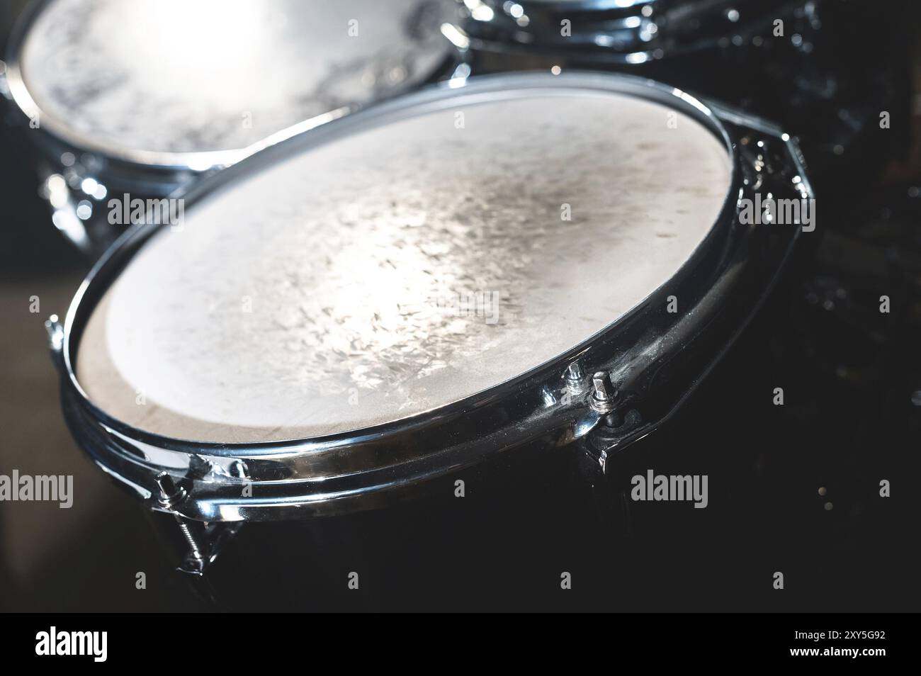 Closeup view of a drum set in a dark studio. Black drum barrels with ...