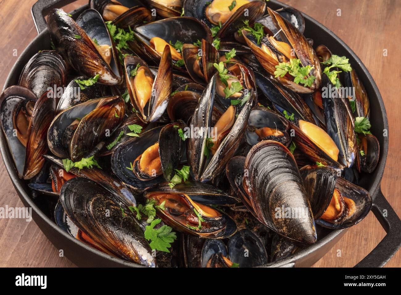 A full braiser of marinara mussels on a dark rustic background, close ...