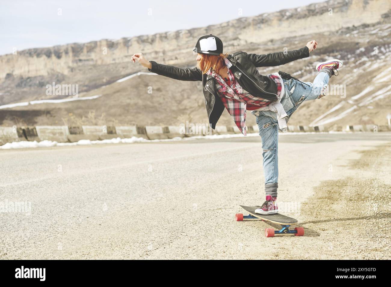 Stylish happy Young girl in a cap and denim overalls balancing in the ...