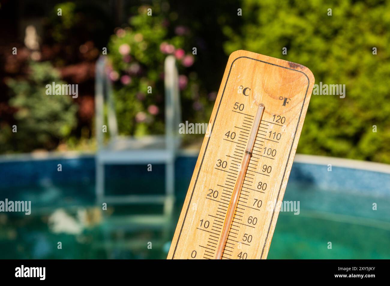 Thermometer showing almost 40 degrees celsius held above a swimming ...