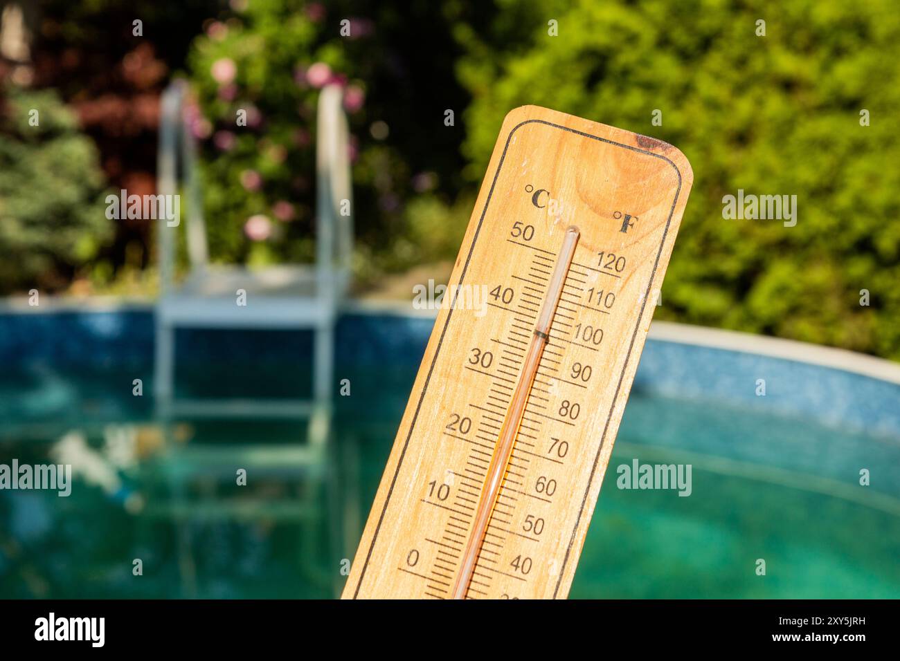 Thermometer showing almost 40 degrees celsius held above a swimming ...