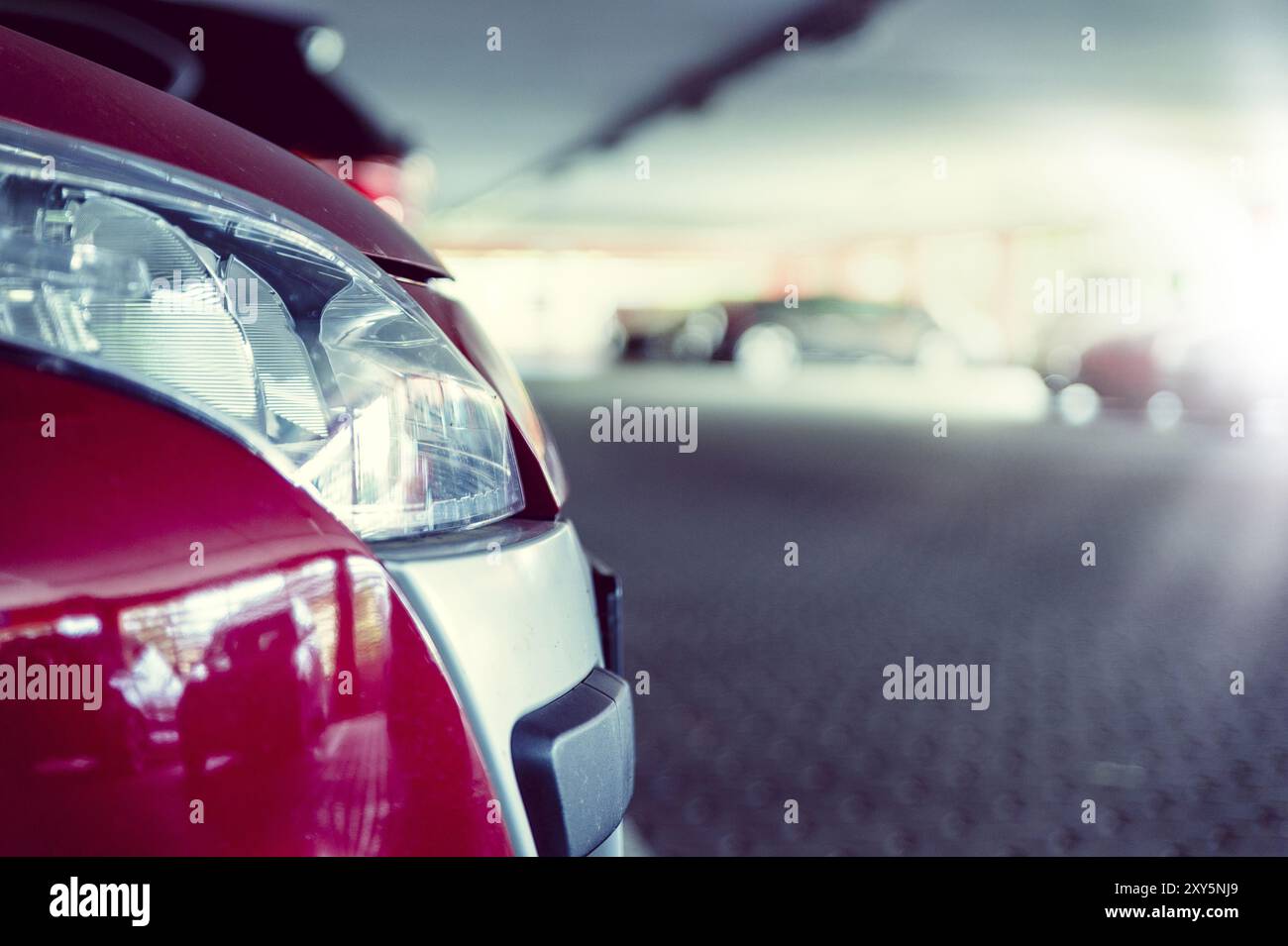 The front part of a car in the light of the low sun under a covered car ...