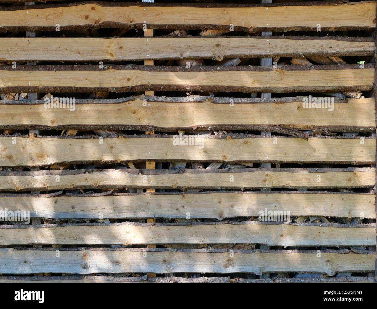 An airy wooden shed for storing split firewood, built from slats with ...