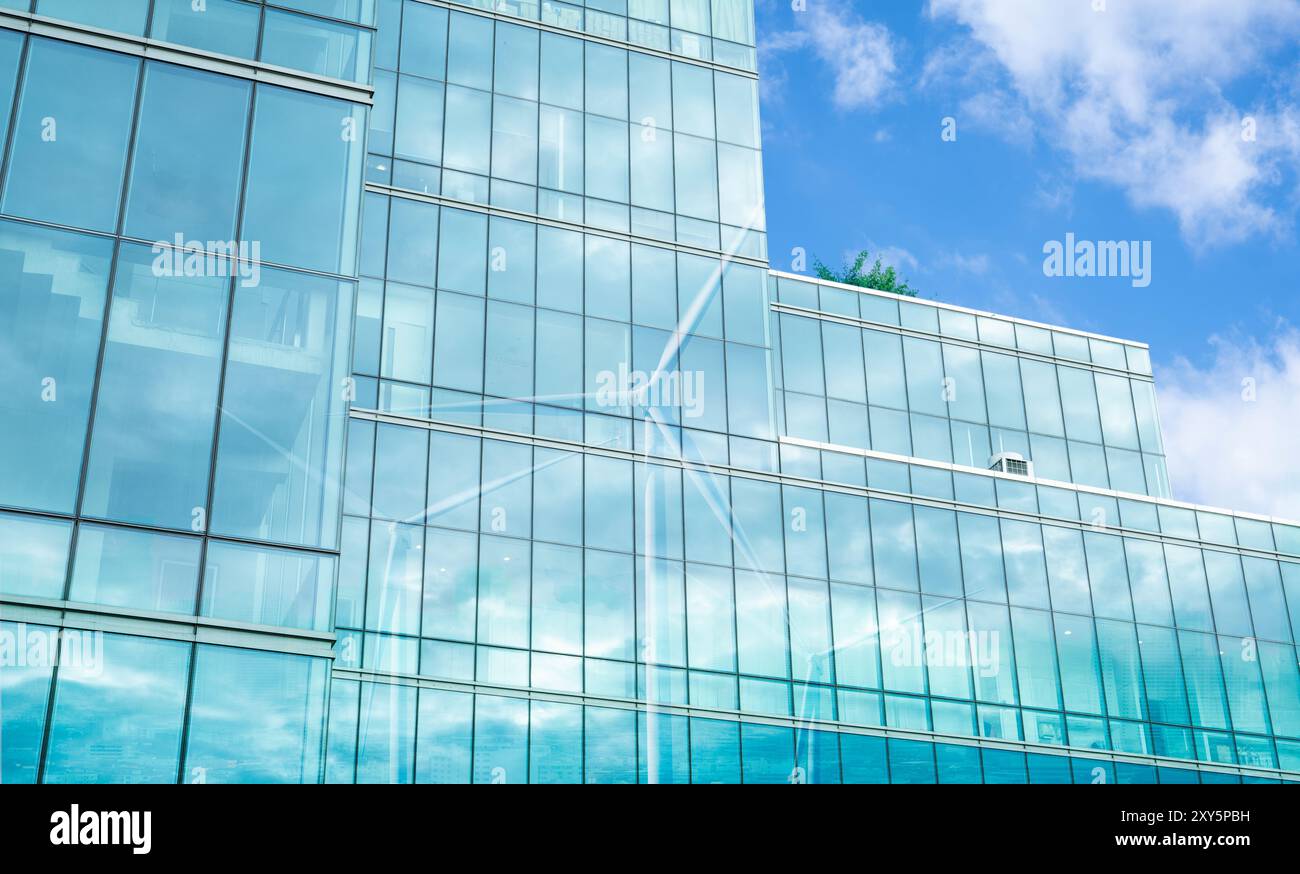 Green corporate building with wind turbine shadow cast on glass facade ...