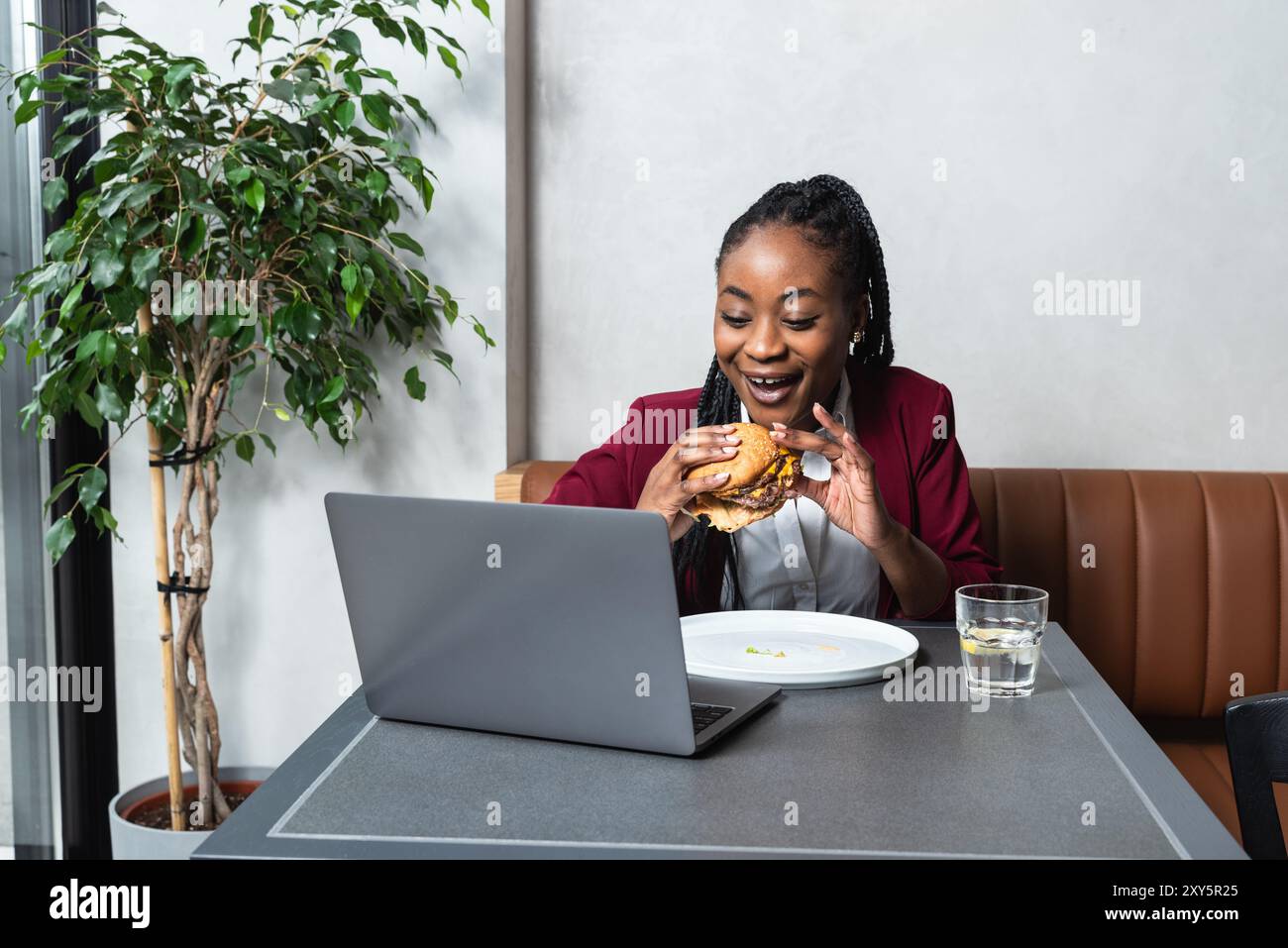 Young business woman working remotely from cafeteria during lunch break ...
