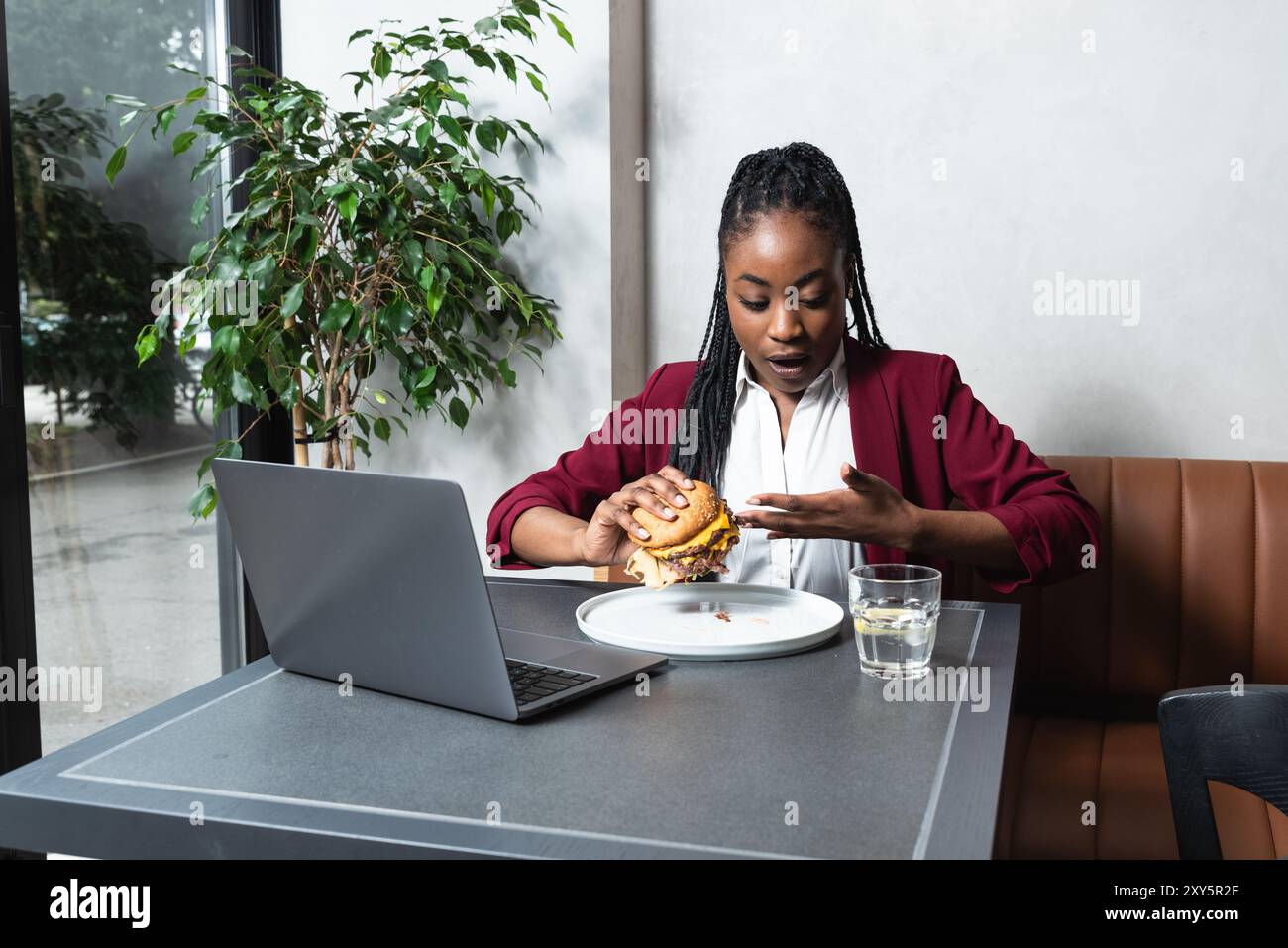 Young business woman working remotely from cafeteria during lunch break ...
