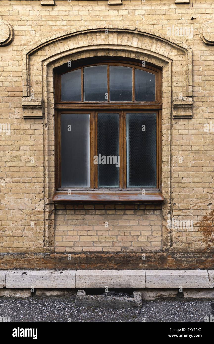 Vintage arched window in the wall of yellow brick. Black glass in a ...