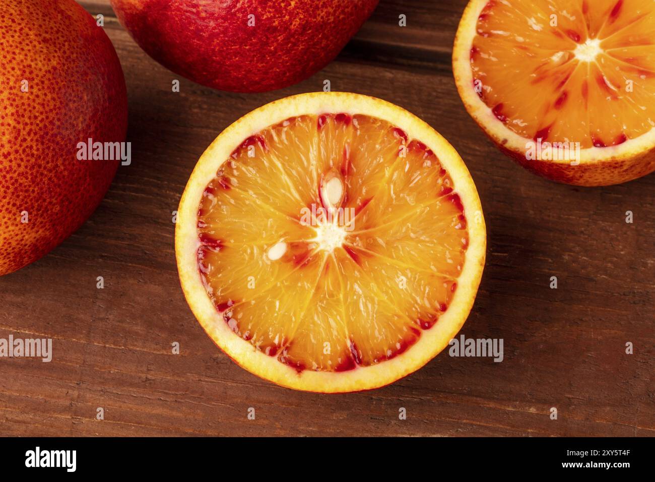 A closeup photo of an organic blood orange on a dark rustic wooden ...