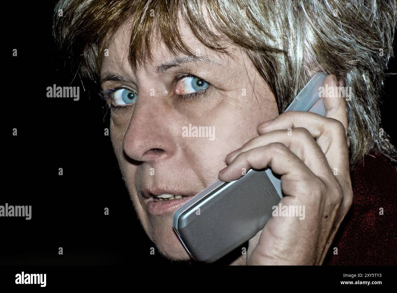 Woman, 50 plus, with an anxious look on her face, talking on a mobile ...
