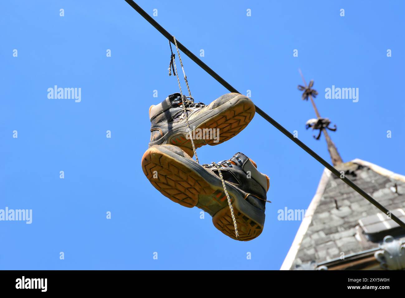 Shoes hanging from an overhead line at a great height Stock Photo - Alamy