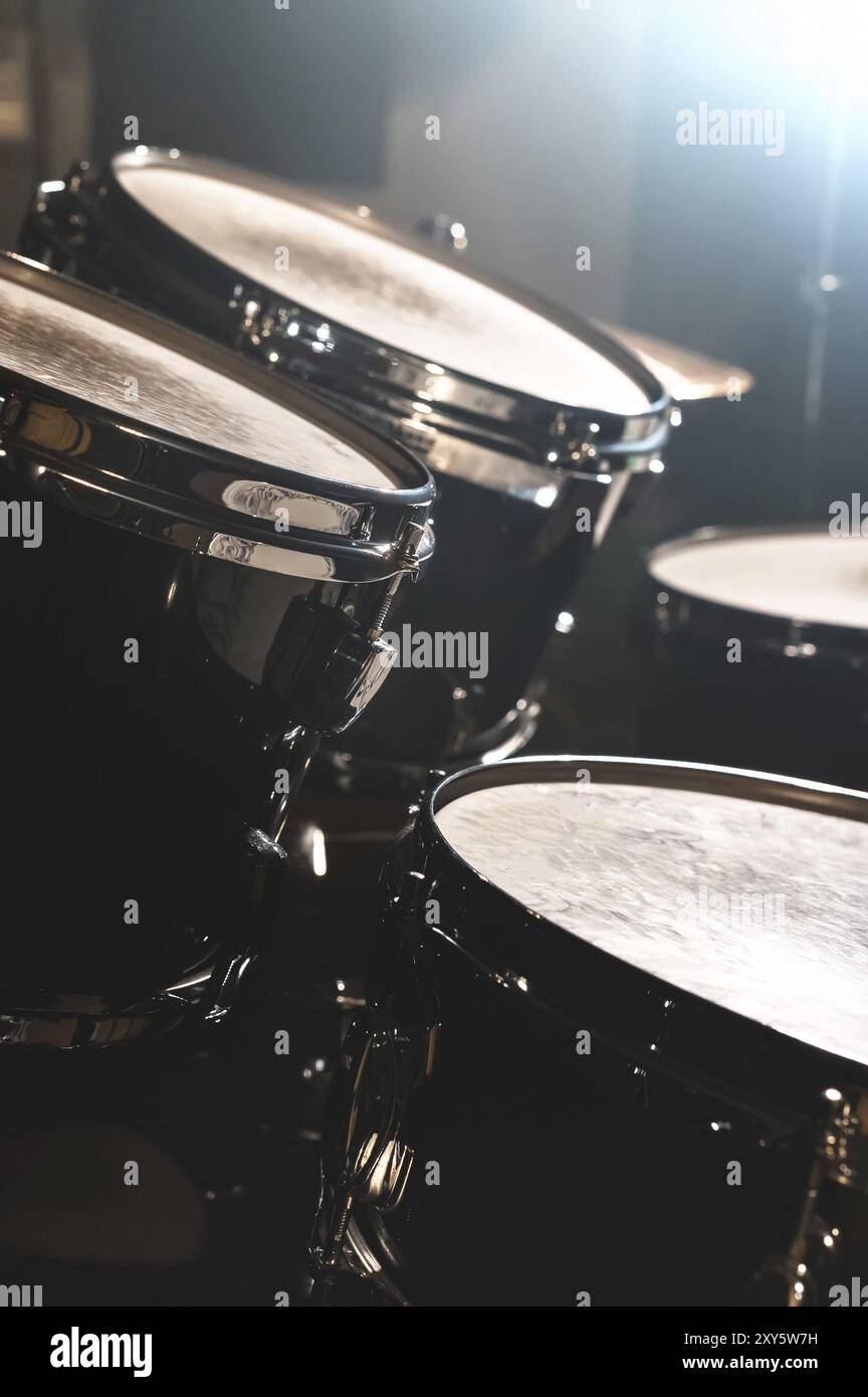 Closeup view of a drum set in a dark studio. Black drum barrels with ...