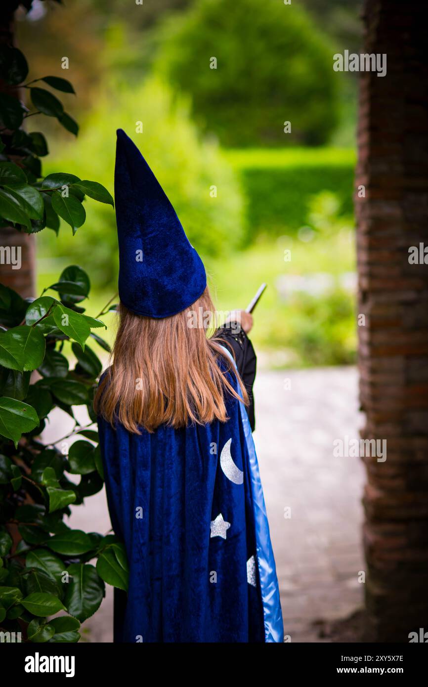 Caucasian blonde child girl in wizard blue costume with cape and hat ...