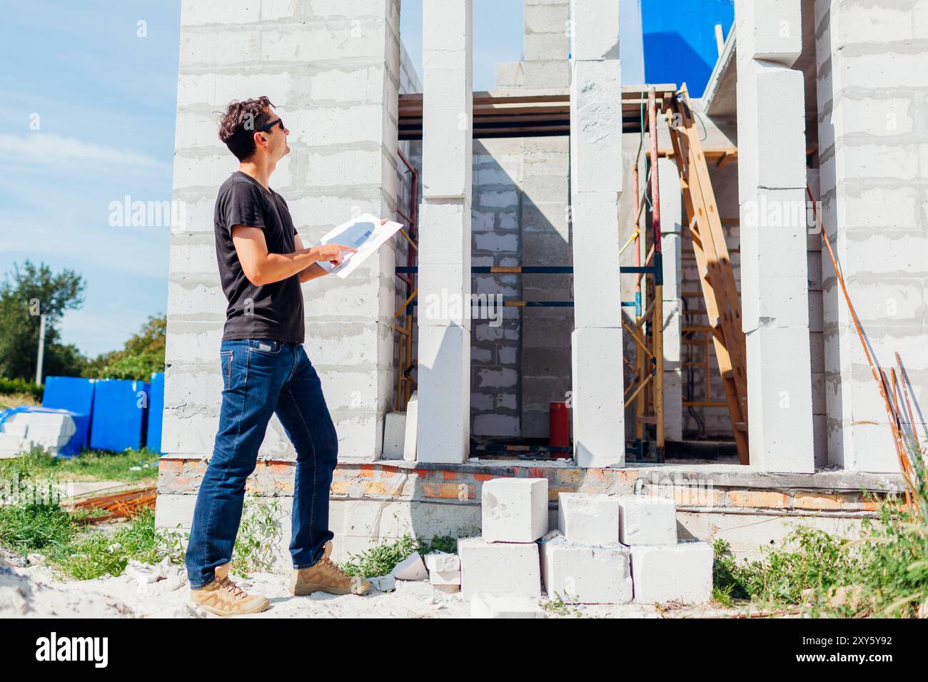 Man architect engineer checking house under construction comparing with ...
