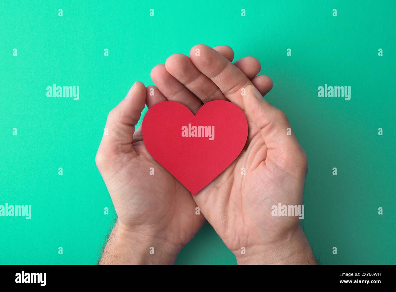 Hand holding red heart cutout on green background. Healthy lifestyle ...