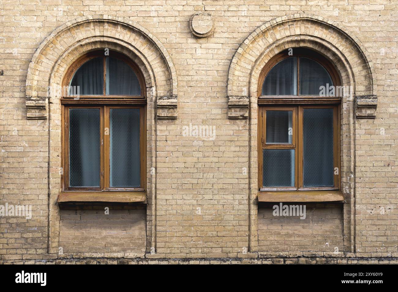 Two vintage arched windows in a wall of yellow bricks. Green, the ...