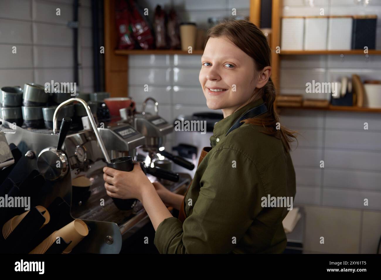 Portrait of woman barista cooking cappuccino on coffeemaker machine ...