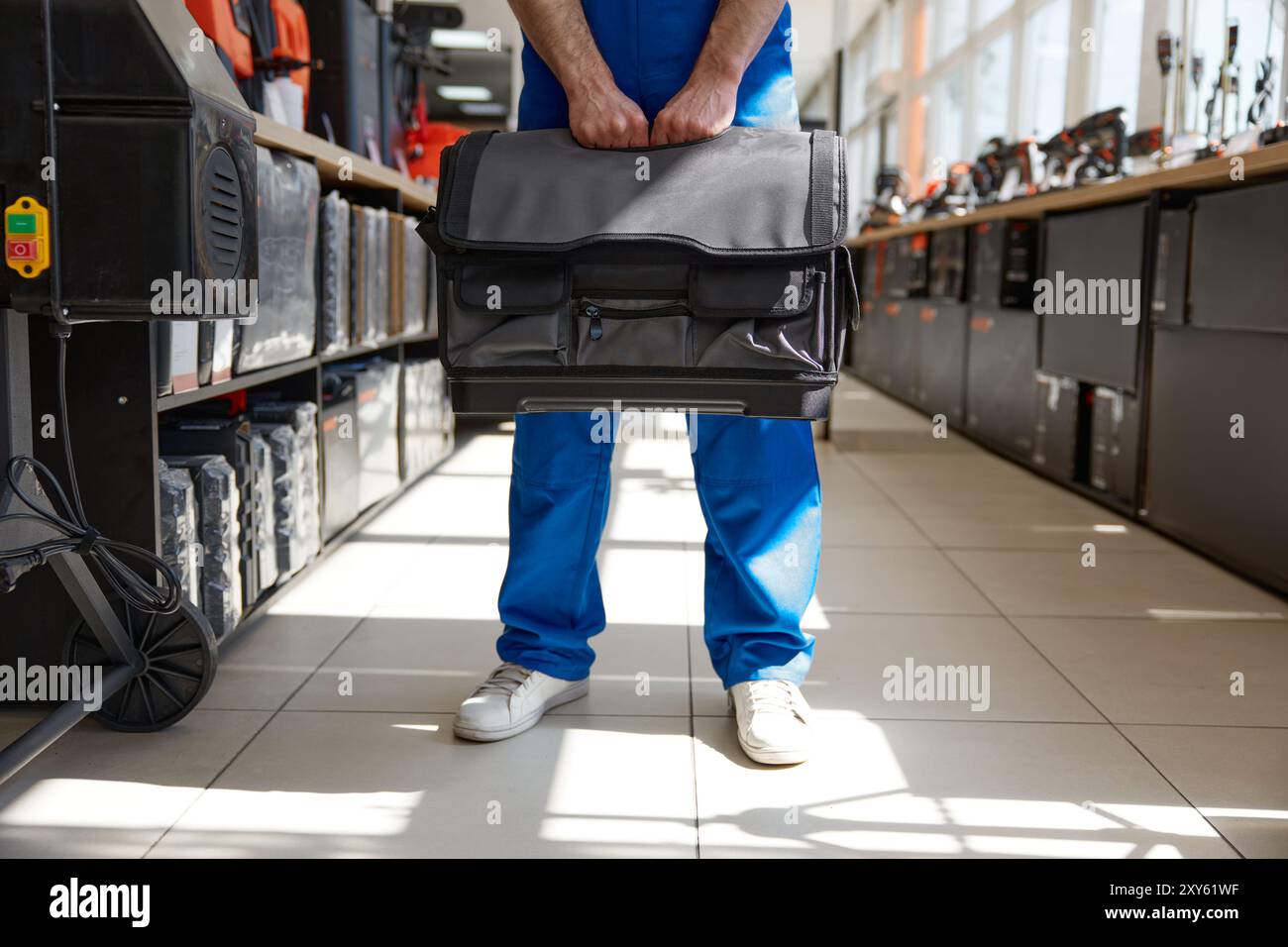 Workman with tool kit box walking between store shelves Stock Photo - Alamy