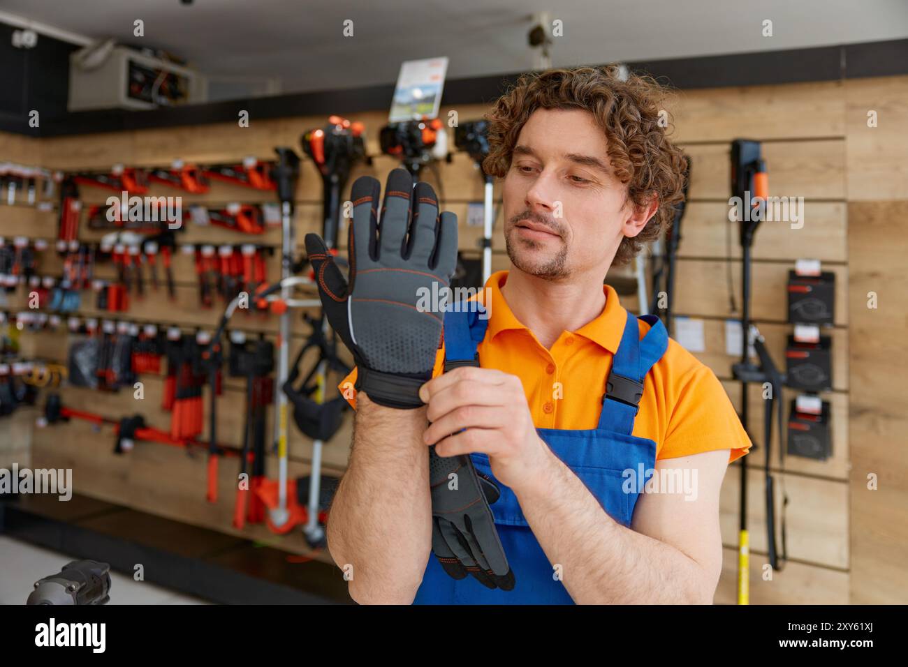 Handsome young hardware store owner putting on construction gloves ...
