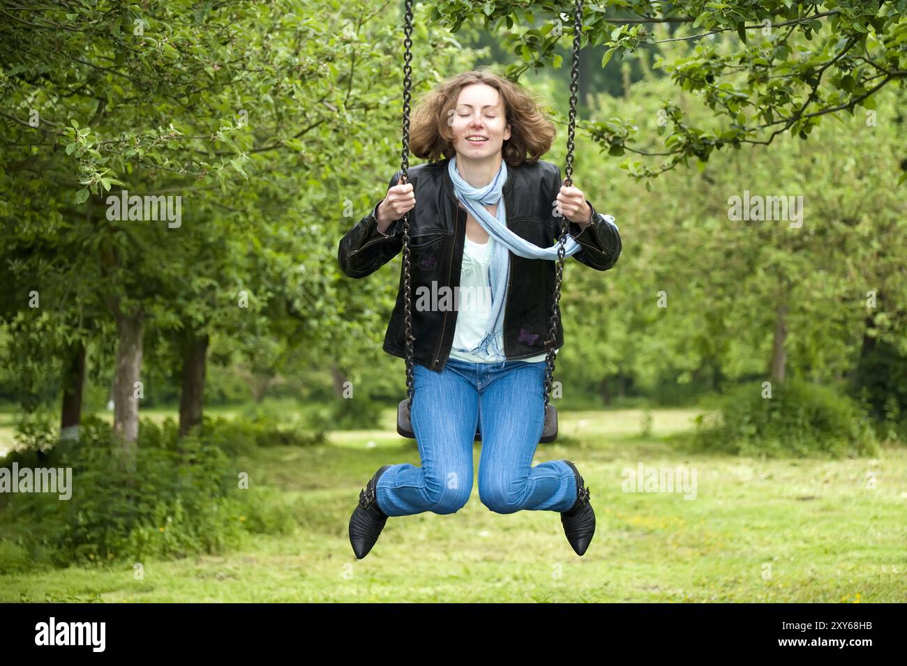 Young woman sitting happily on a swing Stock Photo - Alamy