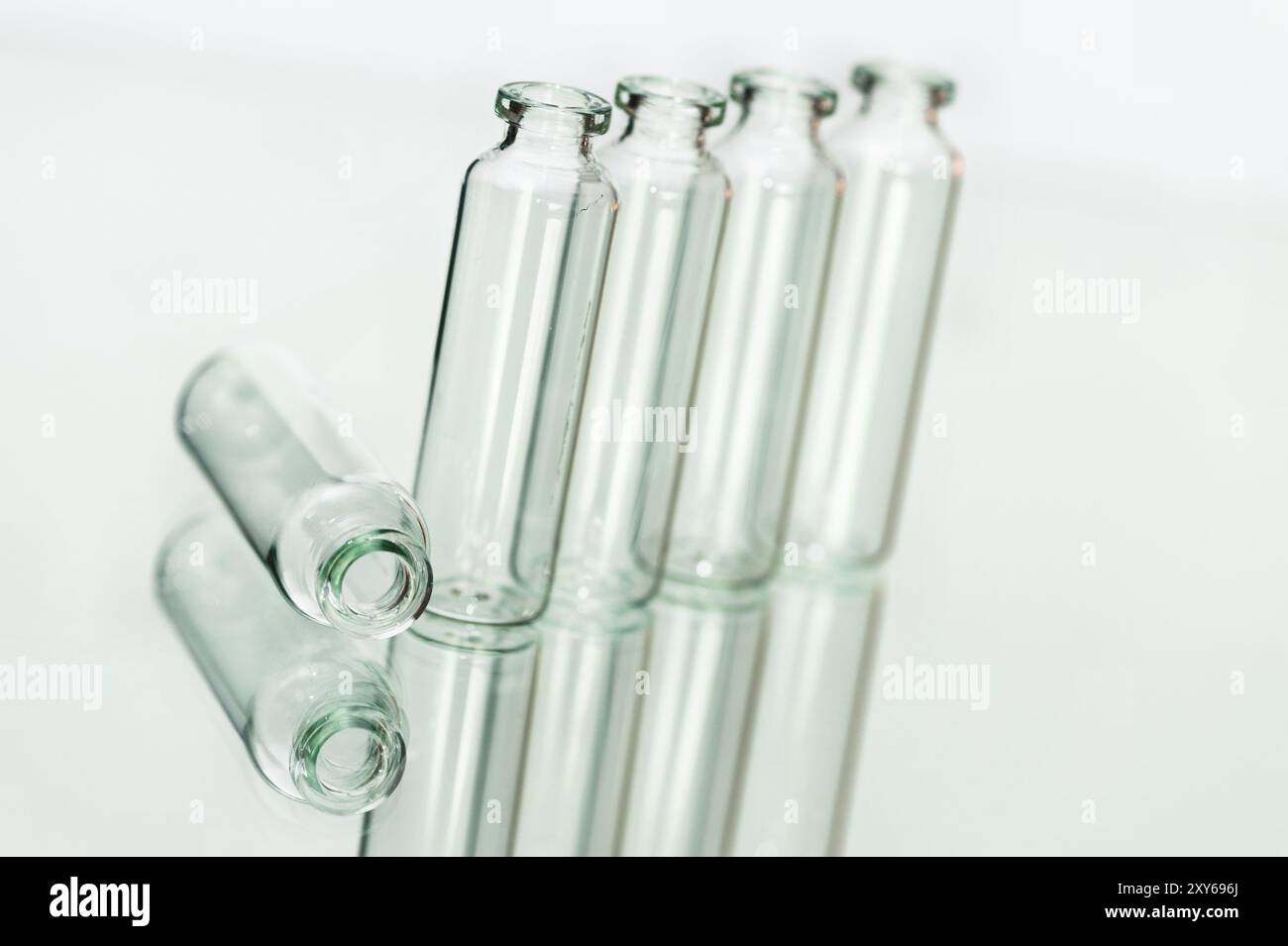 5 small glass tubes lie and stand on a reflective table top Stock Photo ...