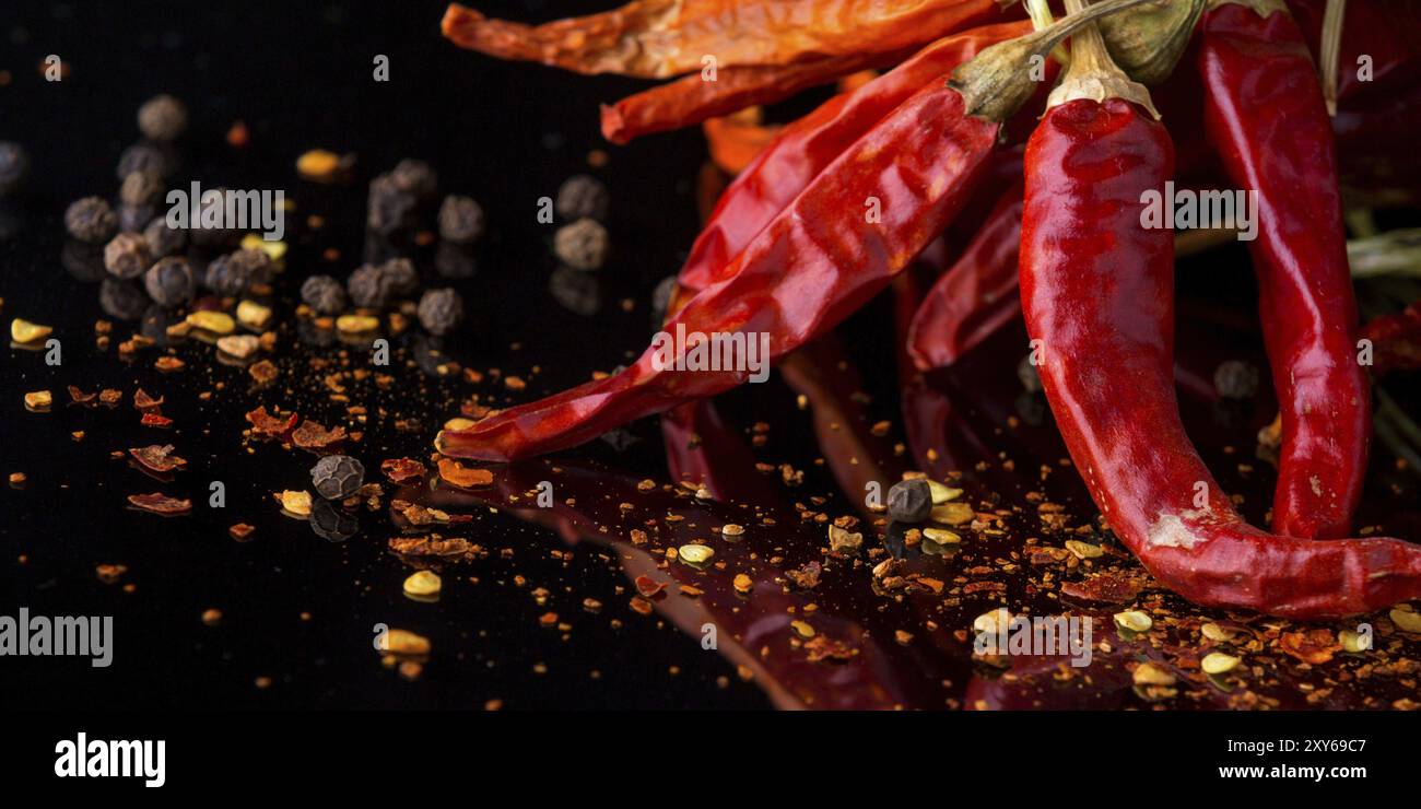 Red chilli pepper and flakes on a black banner background with ...