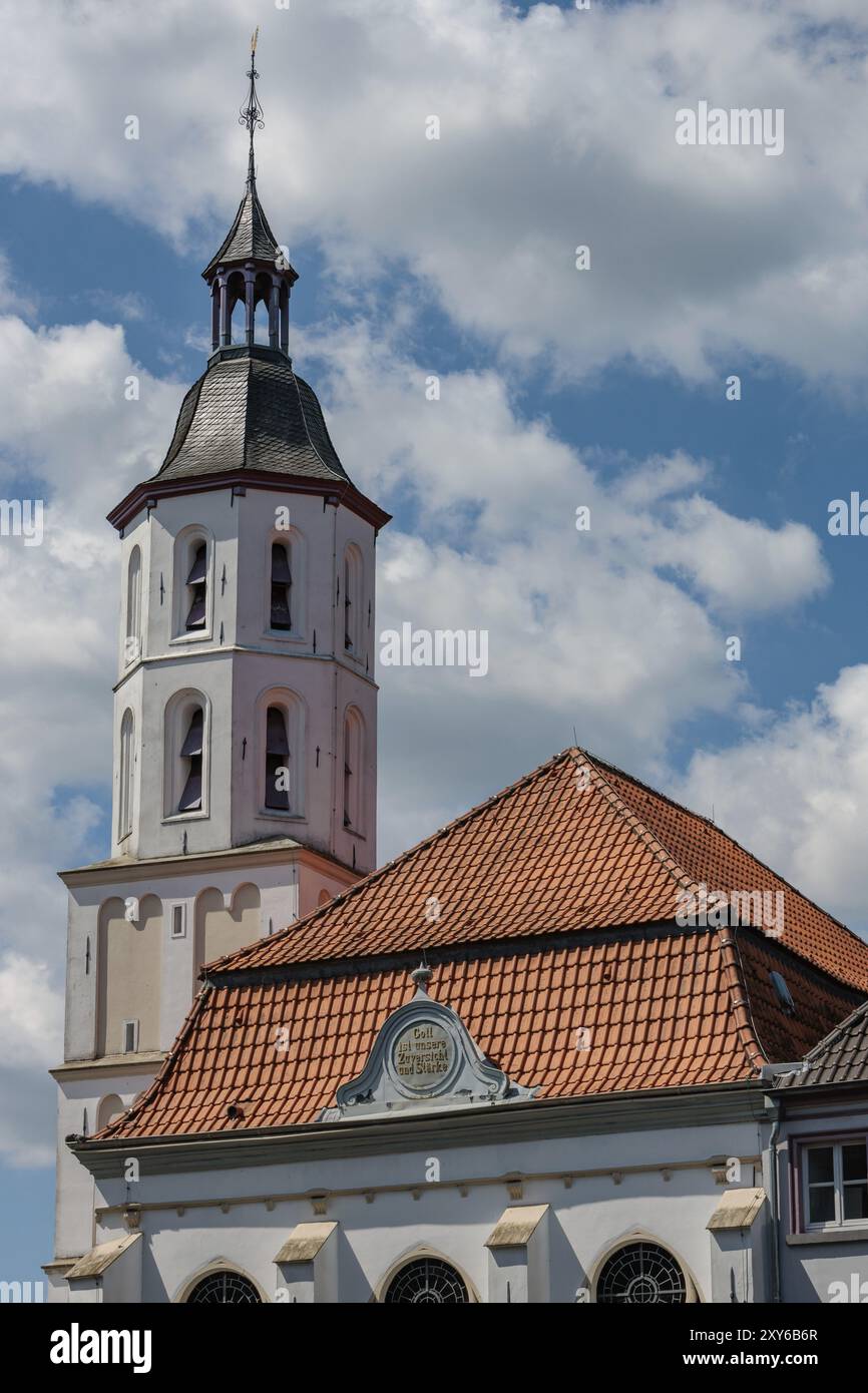 White church tower with pointed roof and building with red tiled roof ...