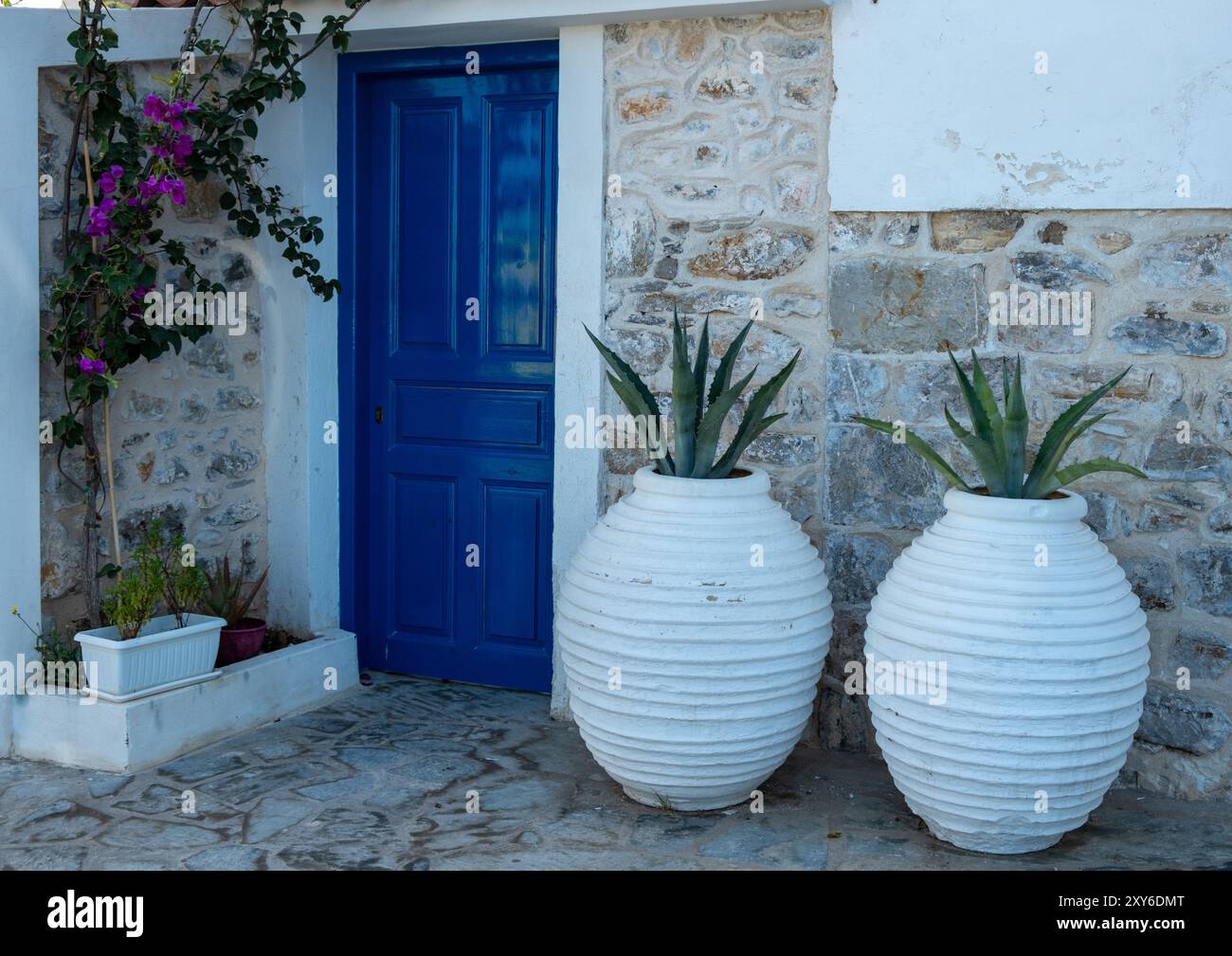 House entrance in a Greek island, blue wooden door and window, blooming ...