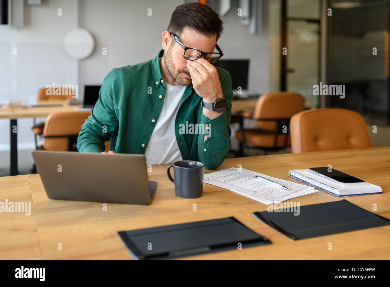 Exhausted male manager rubbing eyes in stress while working over ...