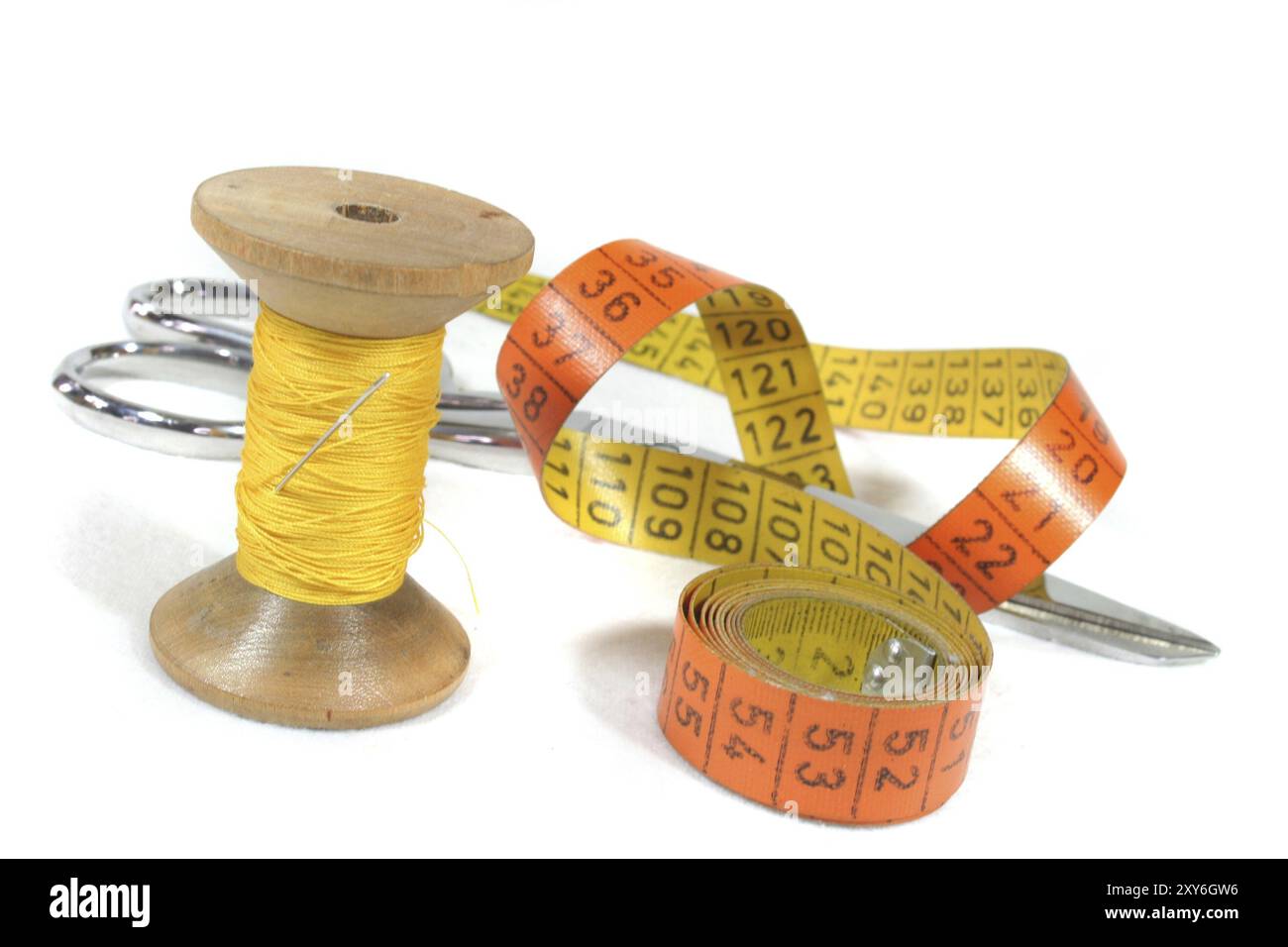 Old spool of thread with needle, tape measure and scissors on a white ...