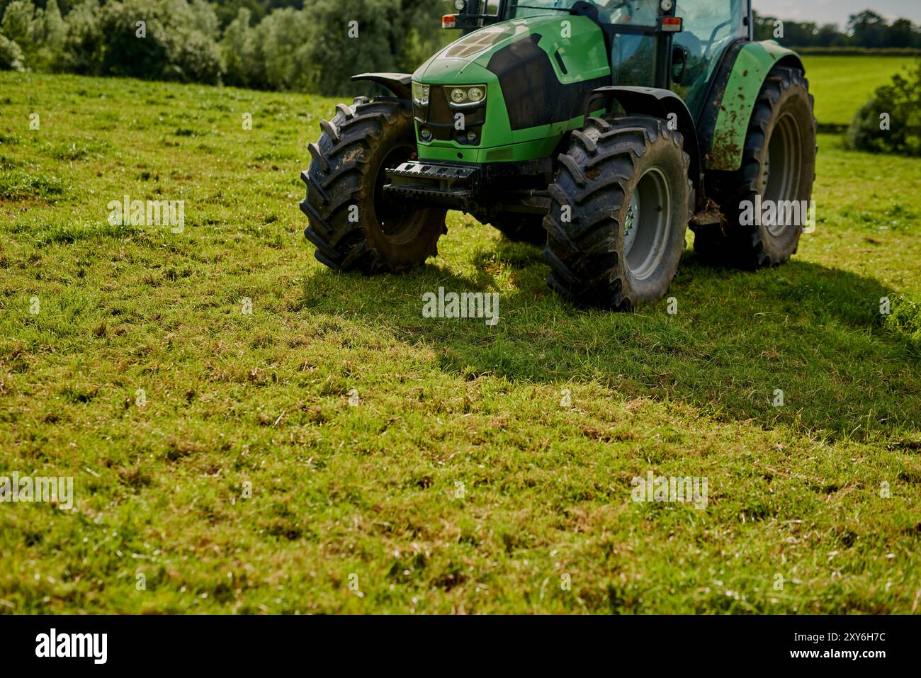 Green tractor, grass field and farming with vehicle for maintenance ...