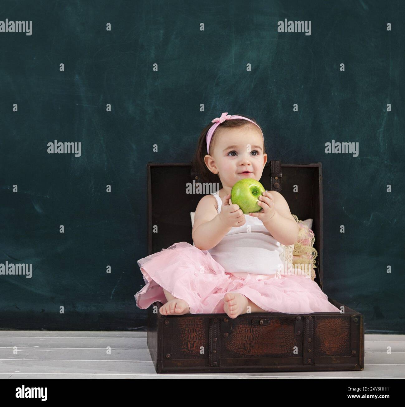 Portrait of the one year old baby girl with apple wearing ballet suit ...