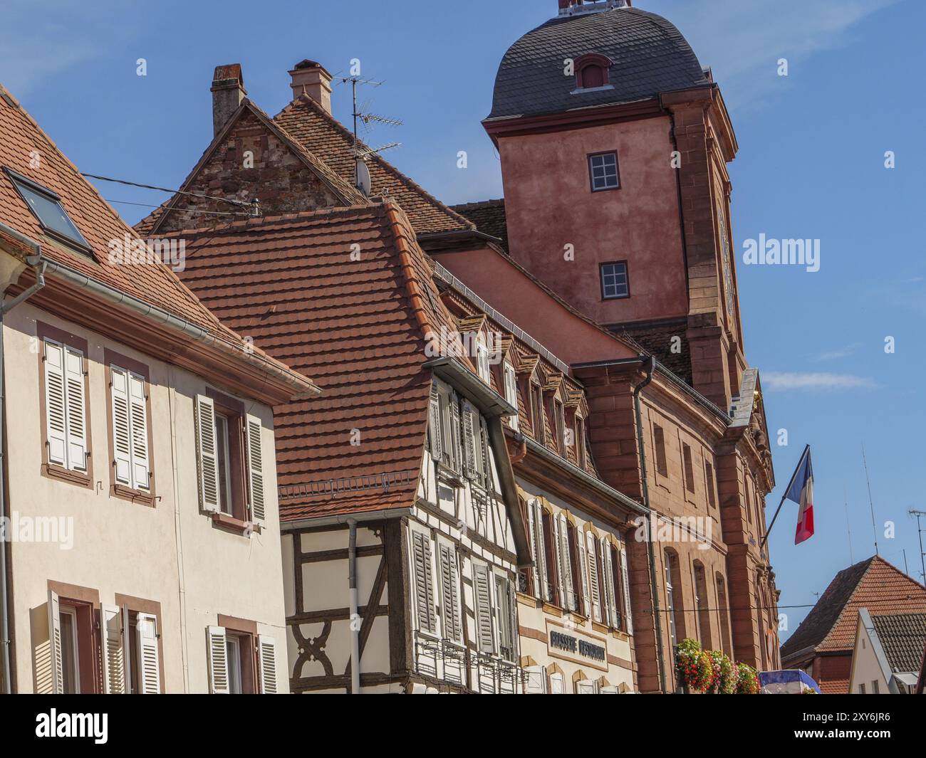 Towers and half-timbered houses with the French flag under a clear blue ...