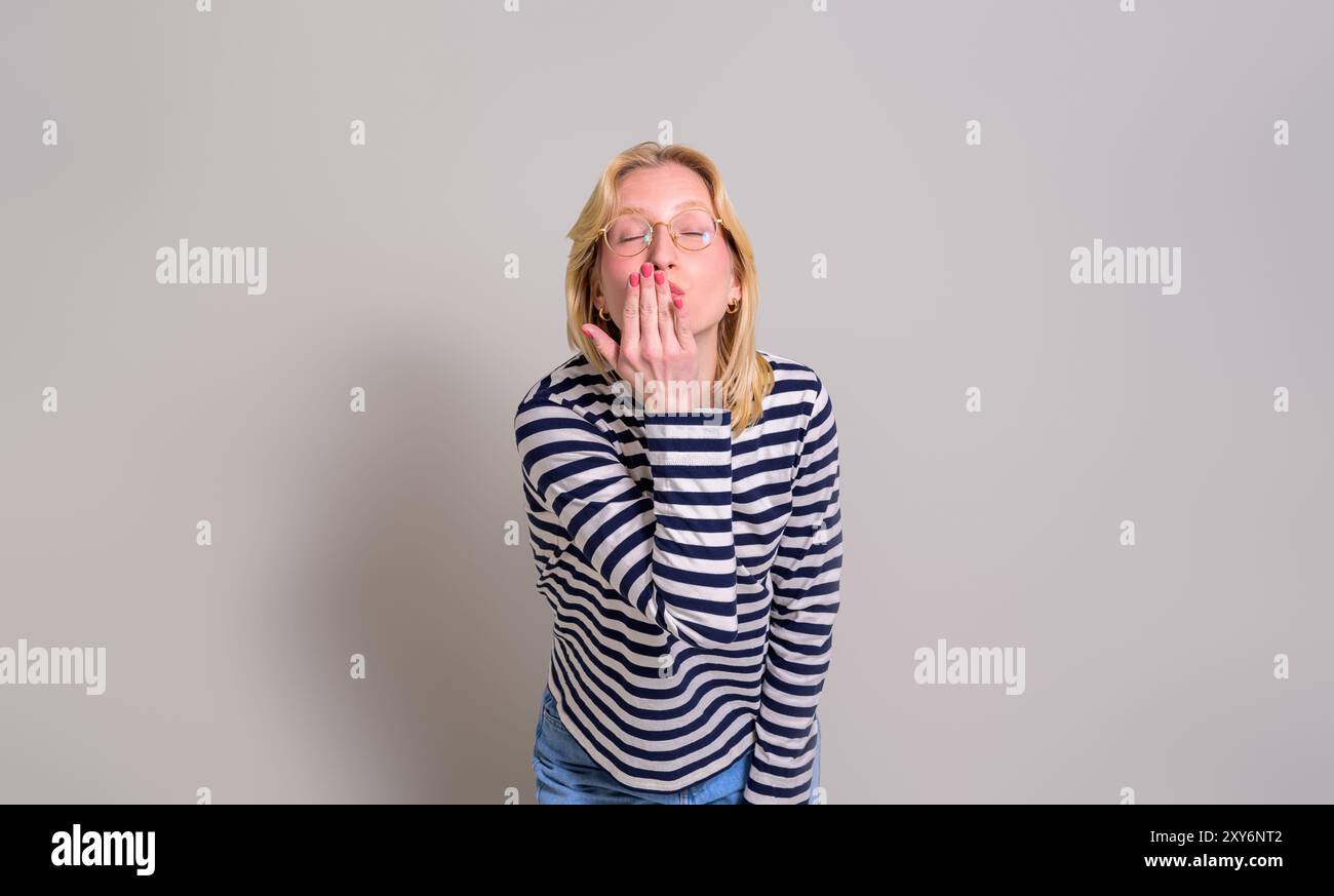 Beautiful young woman with eyes closed blowing kiss on hand while ...
