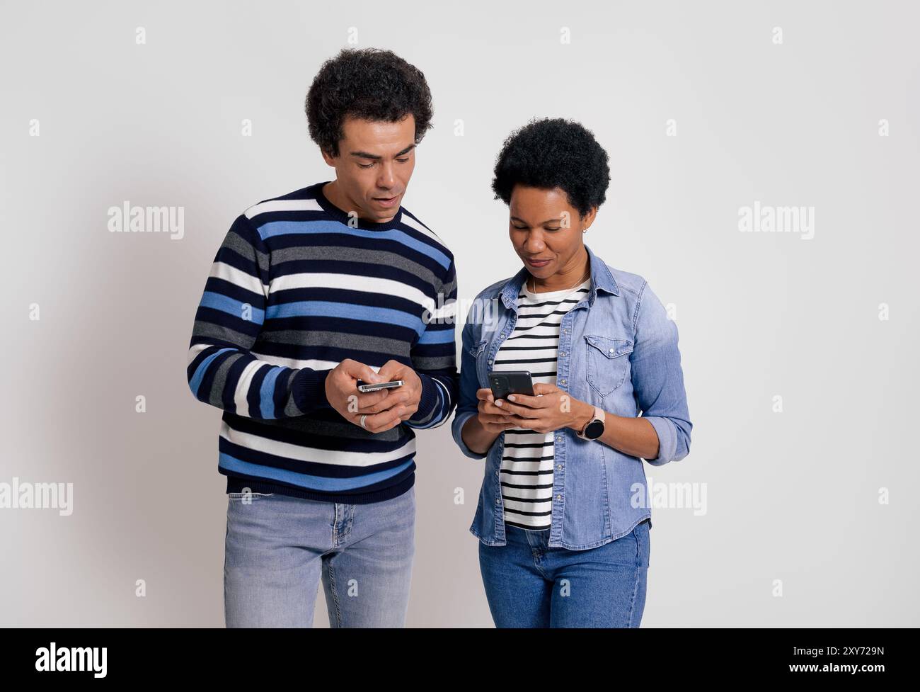 Young man and woman with afro hairstyle texting over smart phones while ...