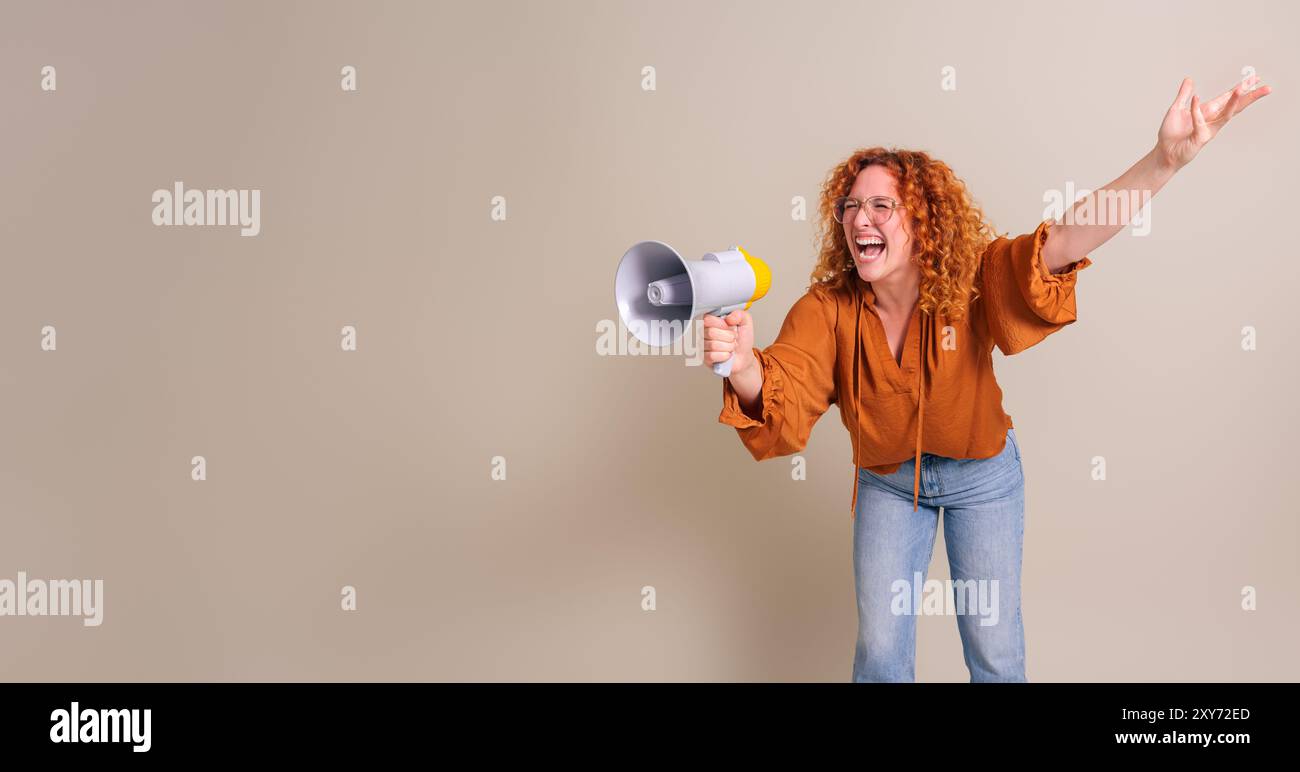 Cheerful young saleswoman with redhead and arm raised shouting over ...