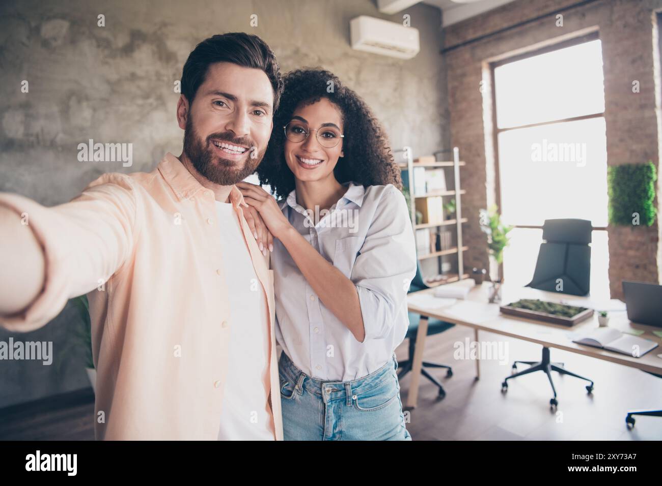 Portrait of two young corporate workers hug make selfie modern loft ...