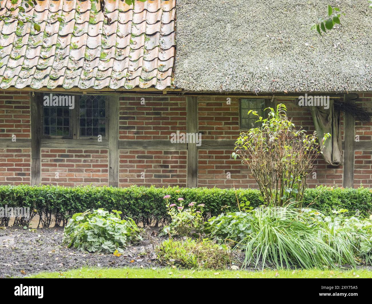 A traditional half-timbered house with a tiled roof and thatched walls ...