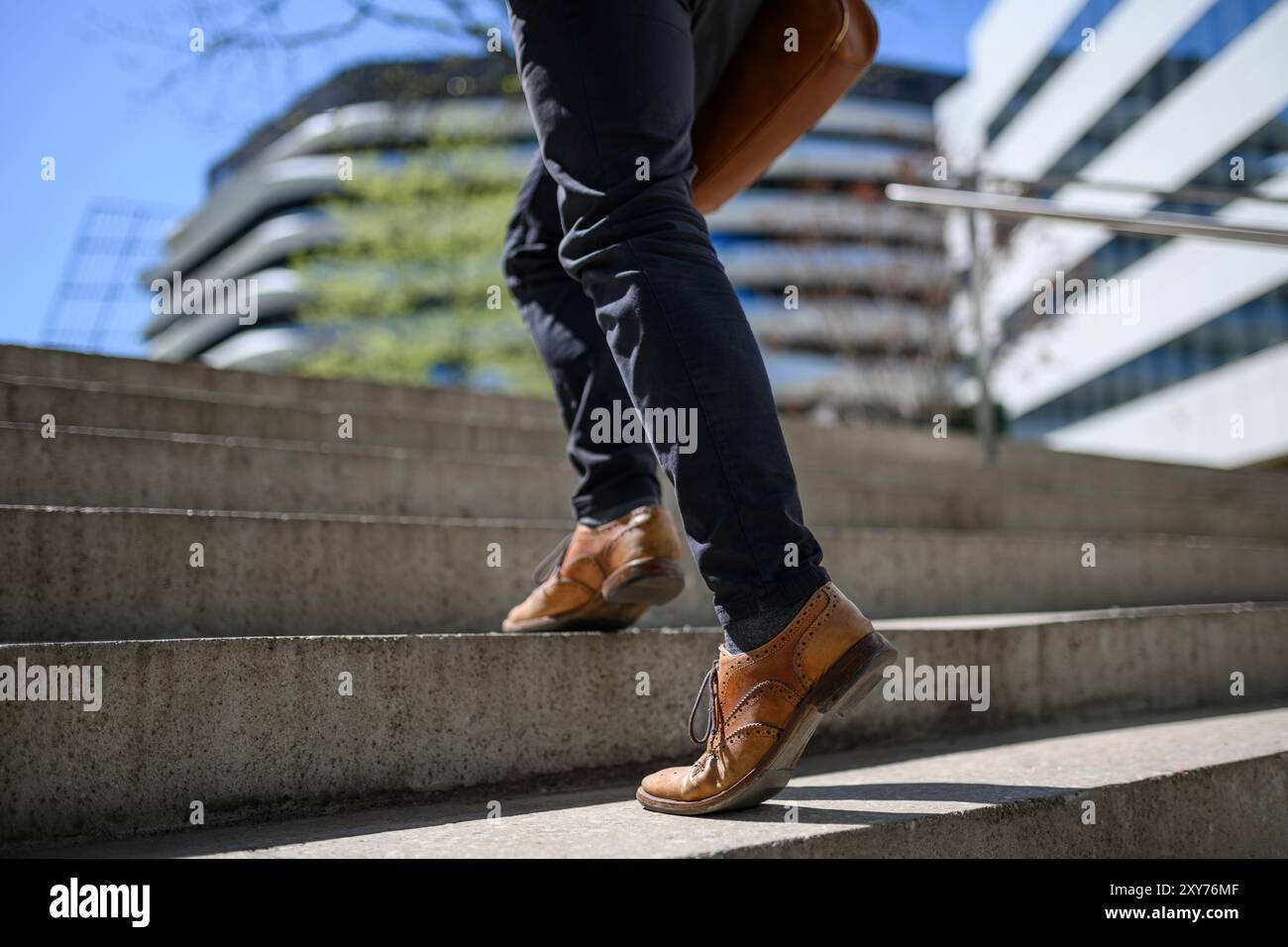 Low section of young businessman wearing leather shoes walking on steps ...