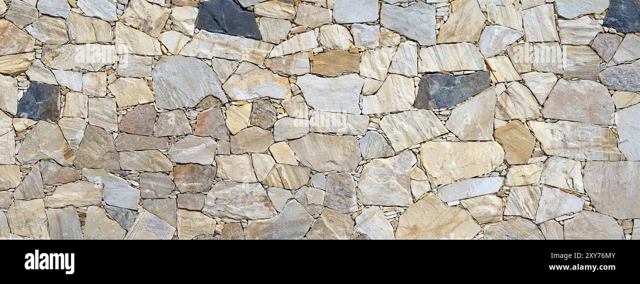 Bright natural stone wall cladding with single dark stones on a facade ...