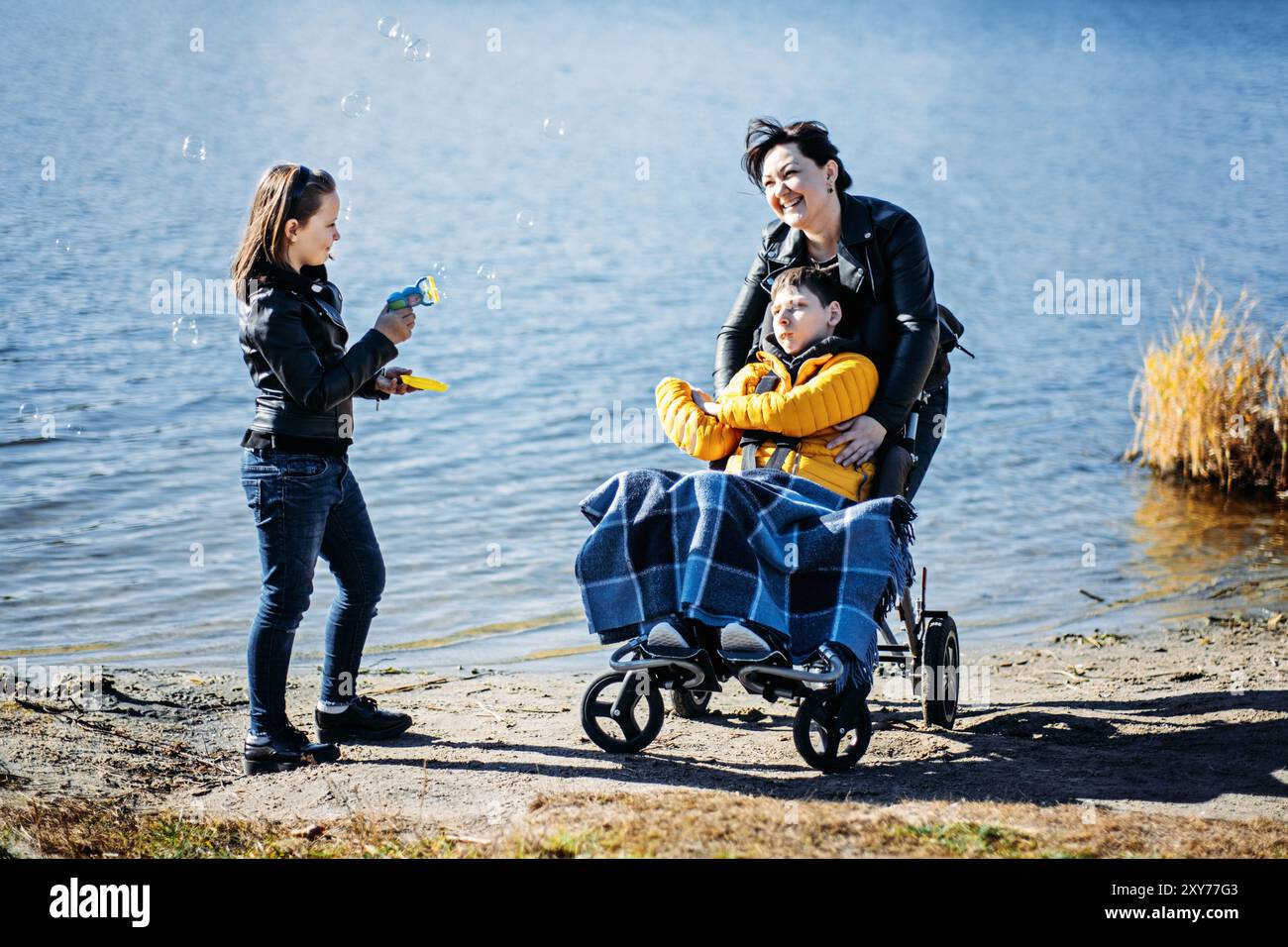 Mother and children engaging in inclusive outdoor activities by the ...