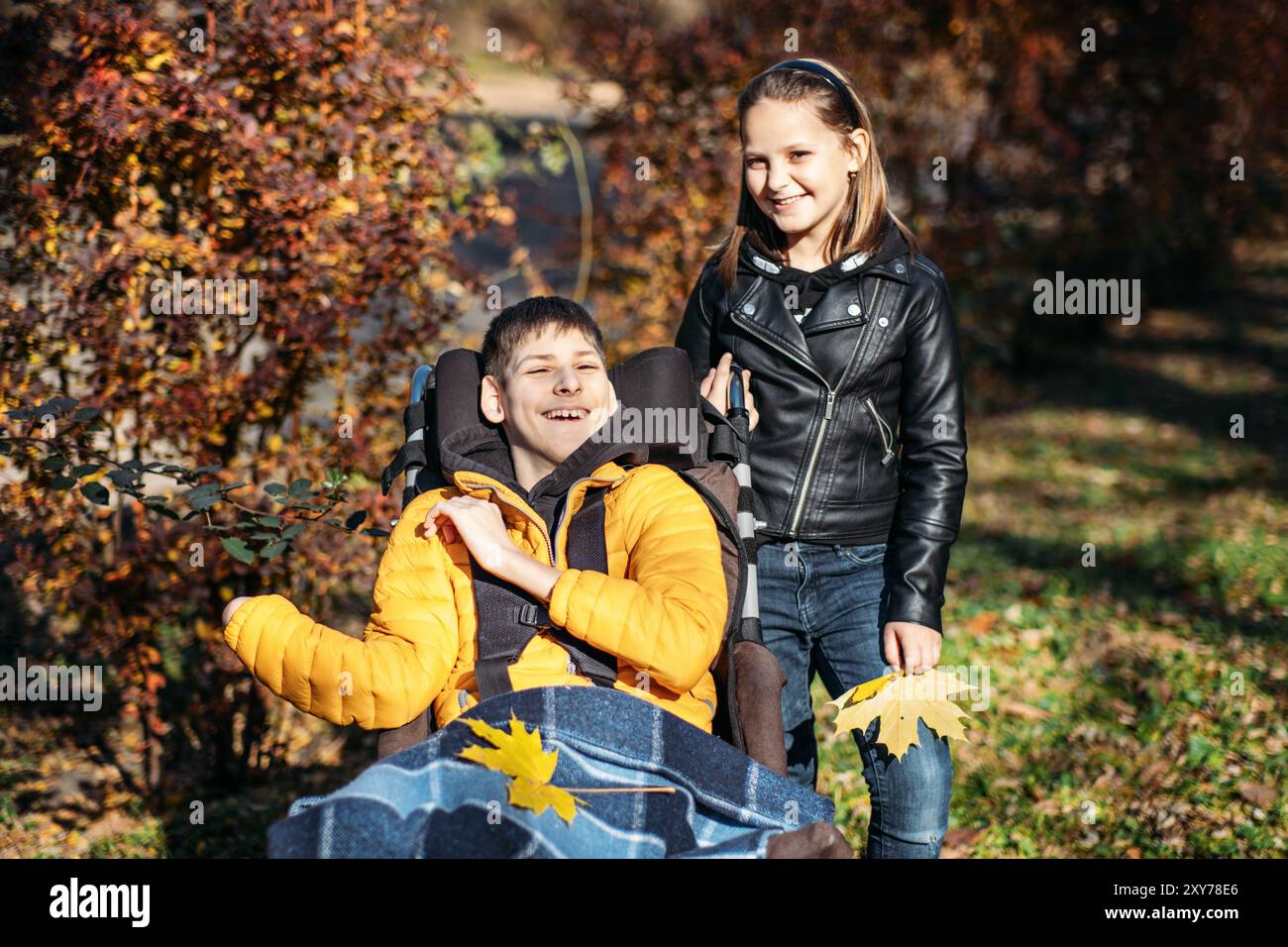 Siblings enjoying outdoor time in park, child in wheelchair, sibling ...