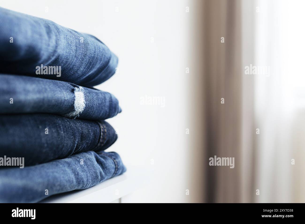 A stack of blue denim jeans or pants. Textile industry concept ...