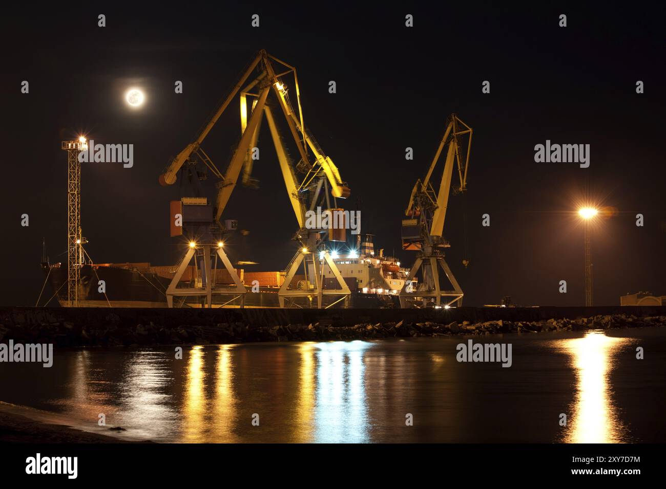 Industrial sea port at the night with moving cranes Stock Photo - Alamy